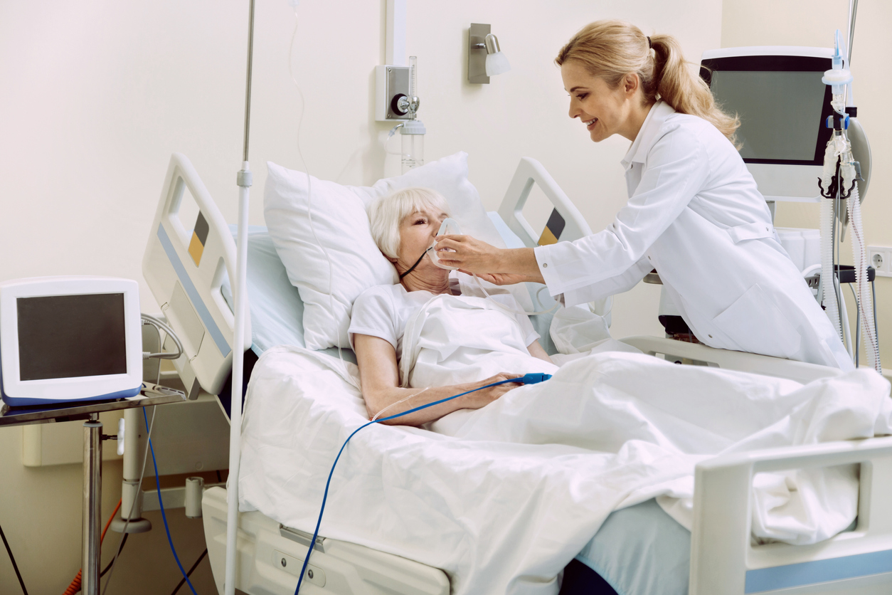 Smiling physician adjusting respiratory support at hospital | Rural ...